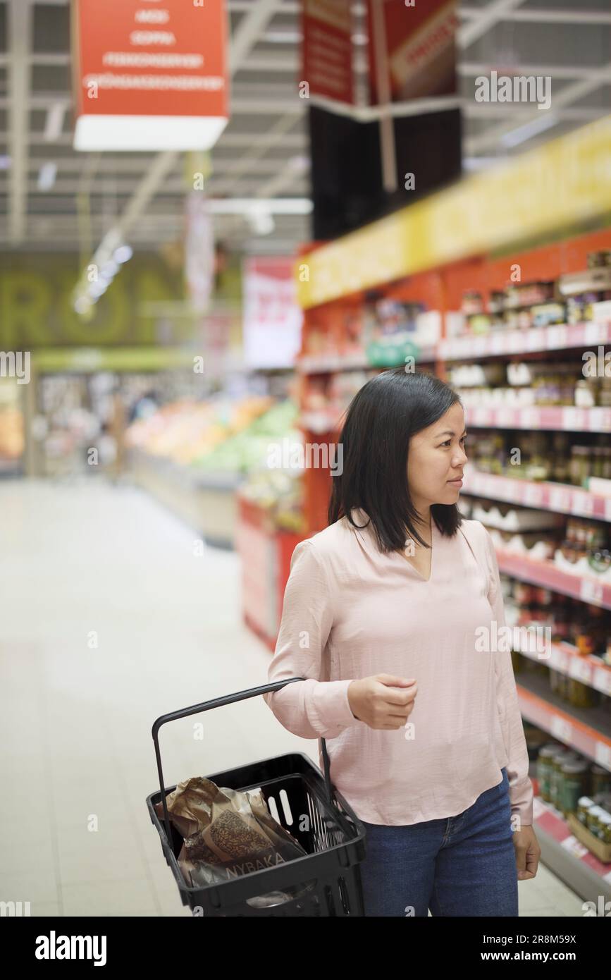 Woman looking at prices during inflation while doing shopping in ...