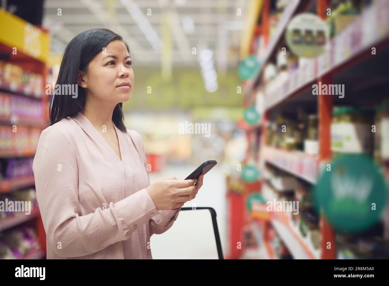 Woman looking at prices during inflation while doing shopping in ...