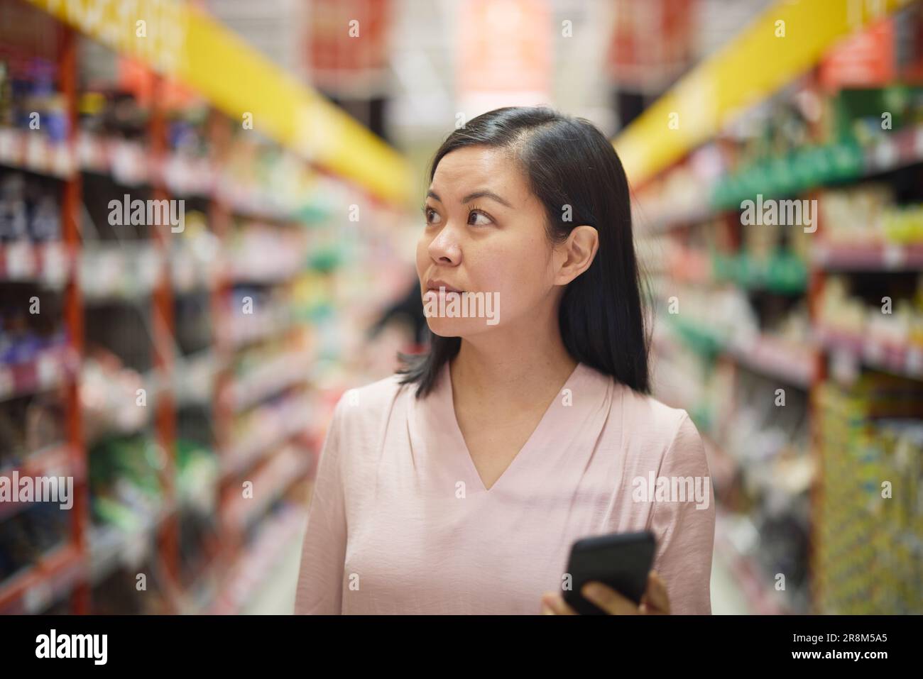 Woman looking at prices during inflation while doing shopping in ...
