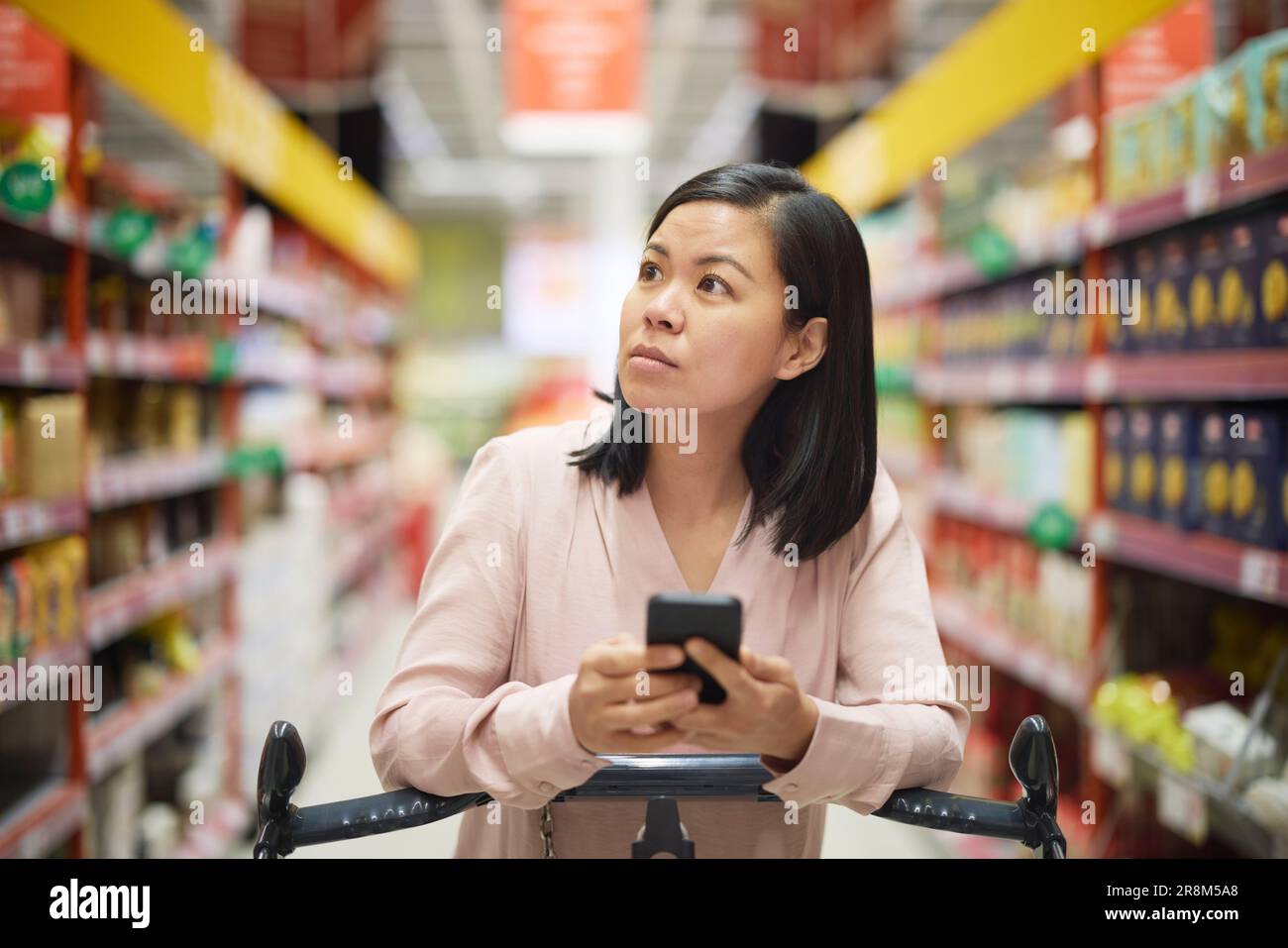 Woman looking at prices during inflation while doing shopping in ...