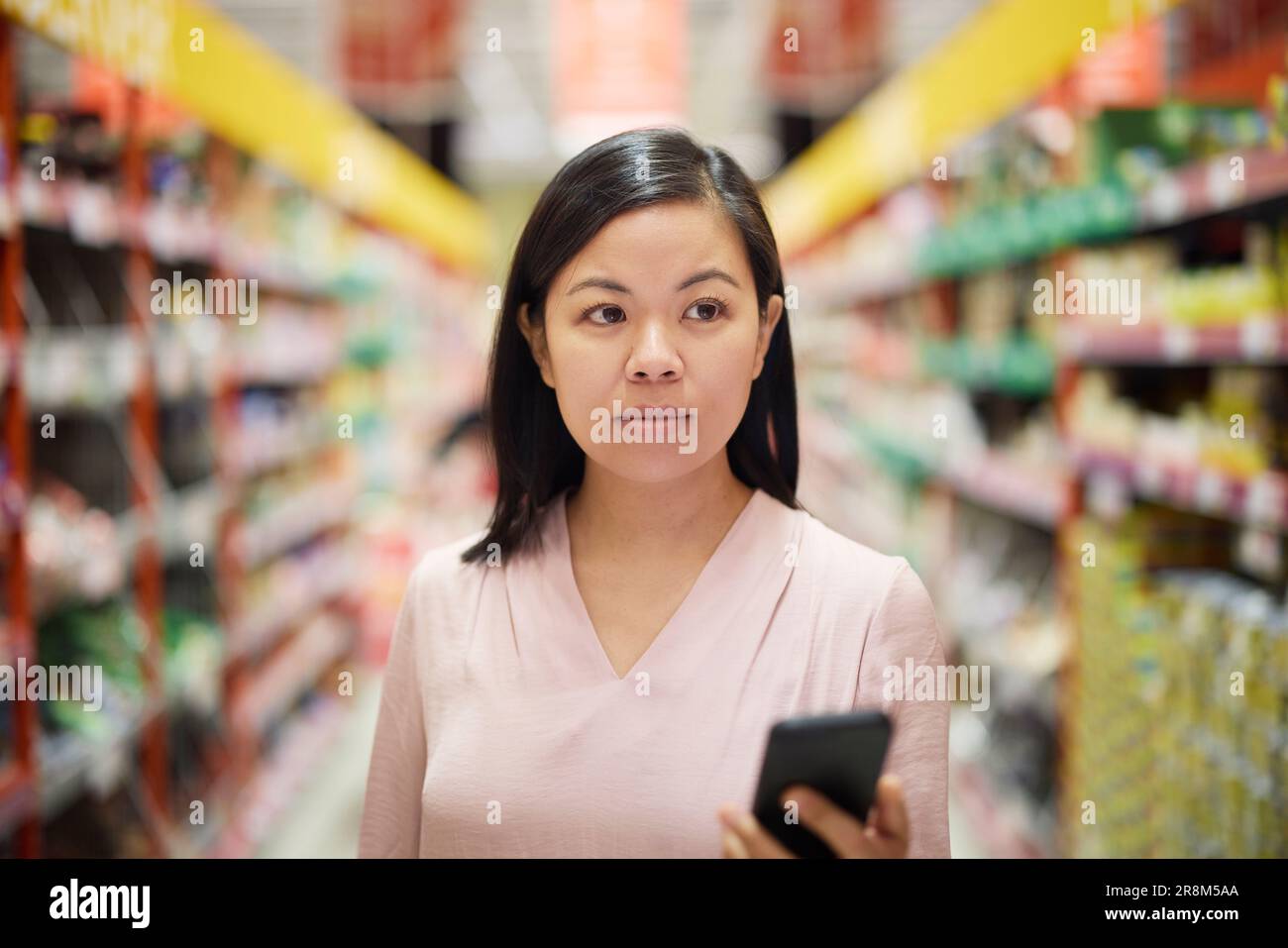 Woman looking at prices during inflation while doing shopping in ...