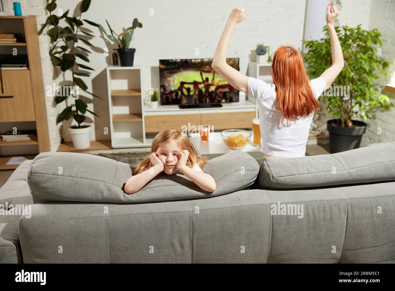 Young excited woman sitting on couch at home and emotionally watching ...