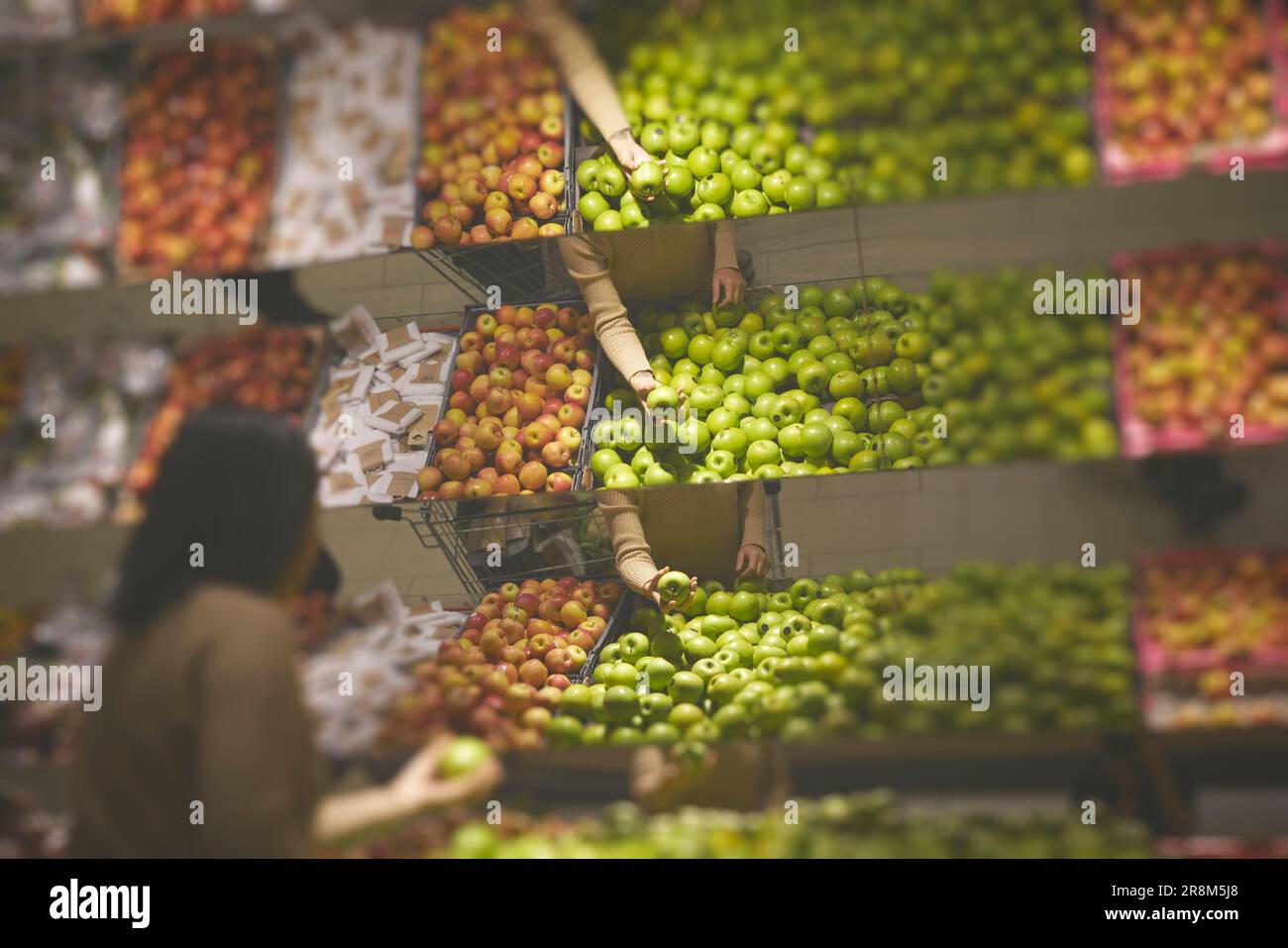 Low angle view of woman choosing apples, fruits reflecting in ...
