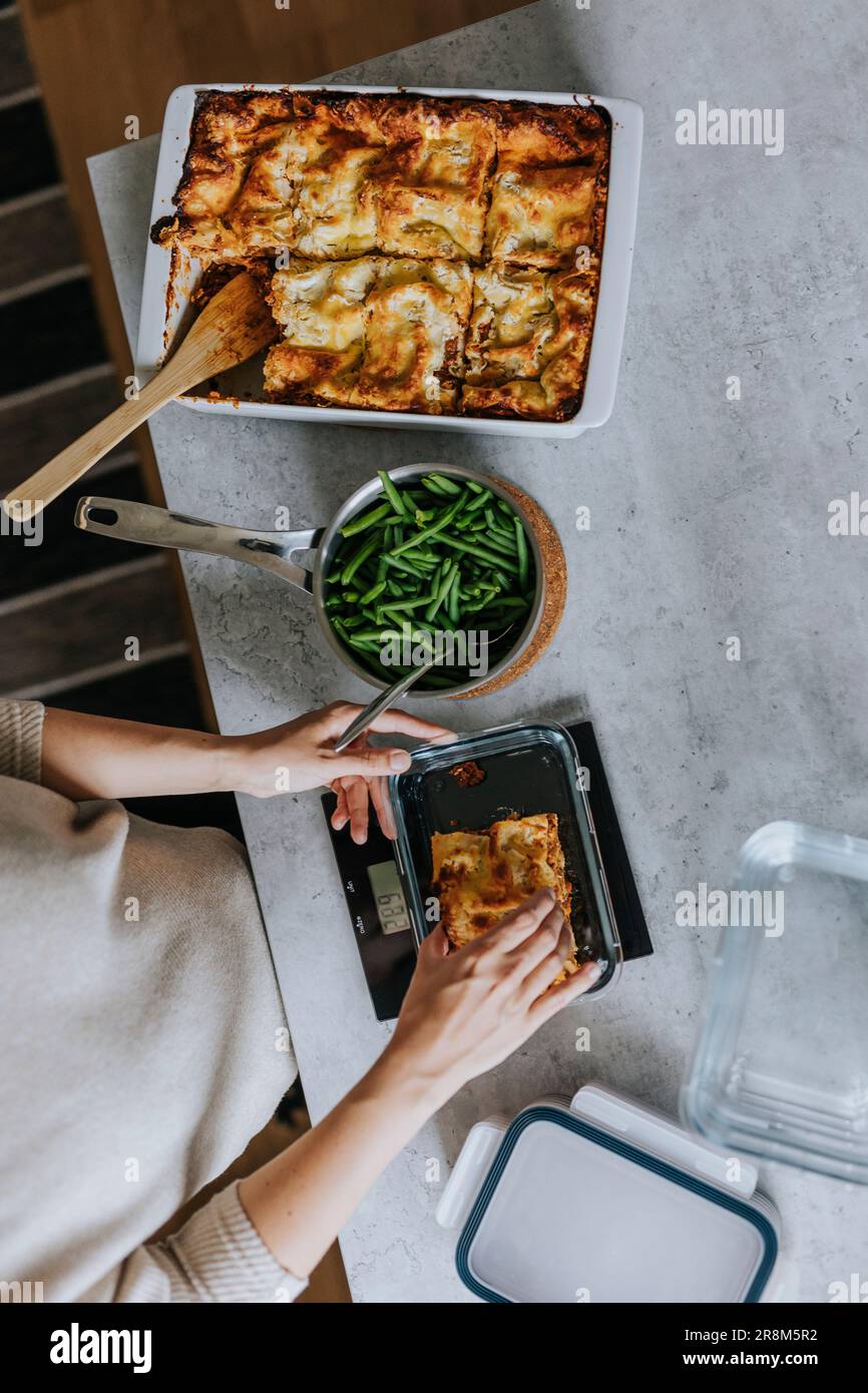 Woman weighing lasagna portions as part of meal prep Stock Photo - Alamy