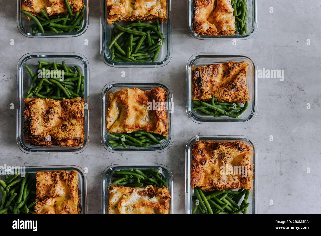 Overhead view of lunch boxes with lasagna and green beans as part of ...