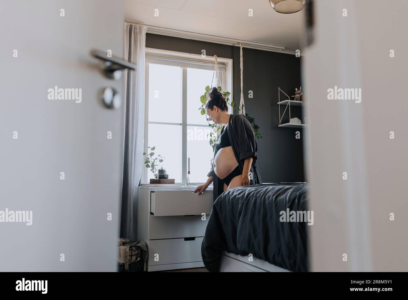 Pregnant woman organizing drawers in bedroom and getting ready for baby ...