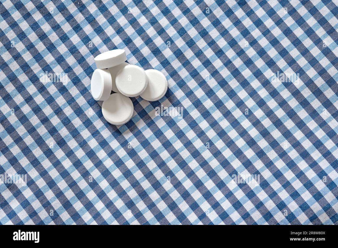 A pile of round pharmaceutical medicine drugs tablets on a white-blue ...