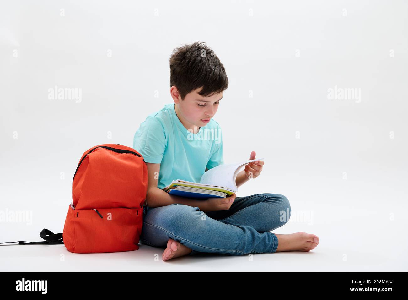 Smart teen school boy leafing through his copybook, doing homework ...