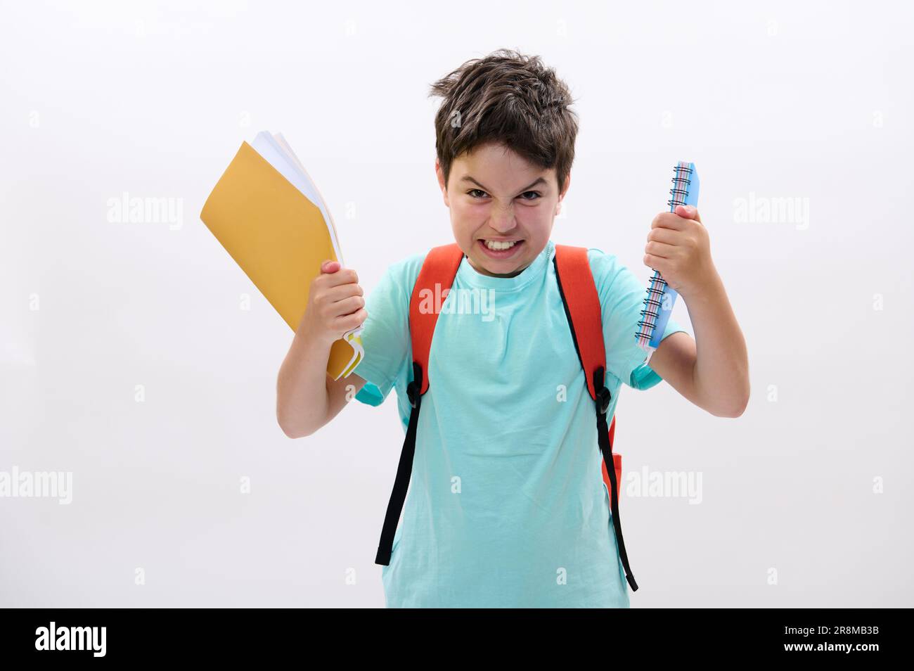 Confused angry schoolboy holding textbooks, expressing anger ...