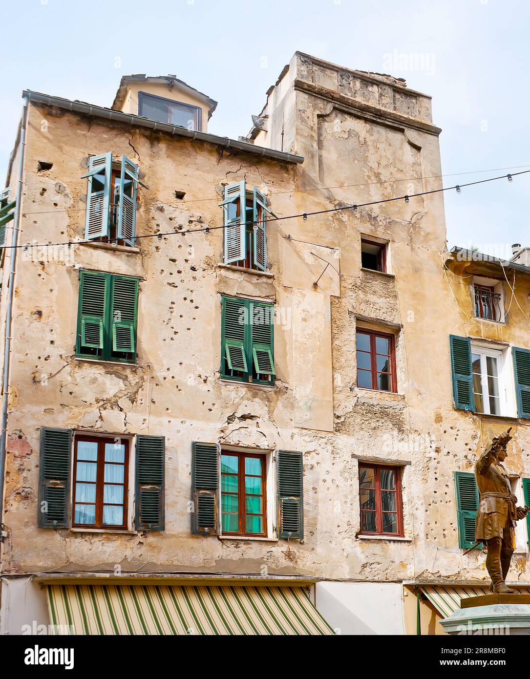 The shabby historic house, riddled with bullet holes with a monument to ...