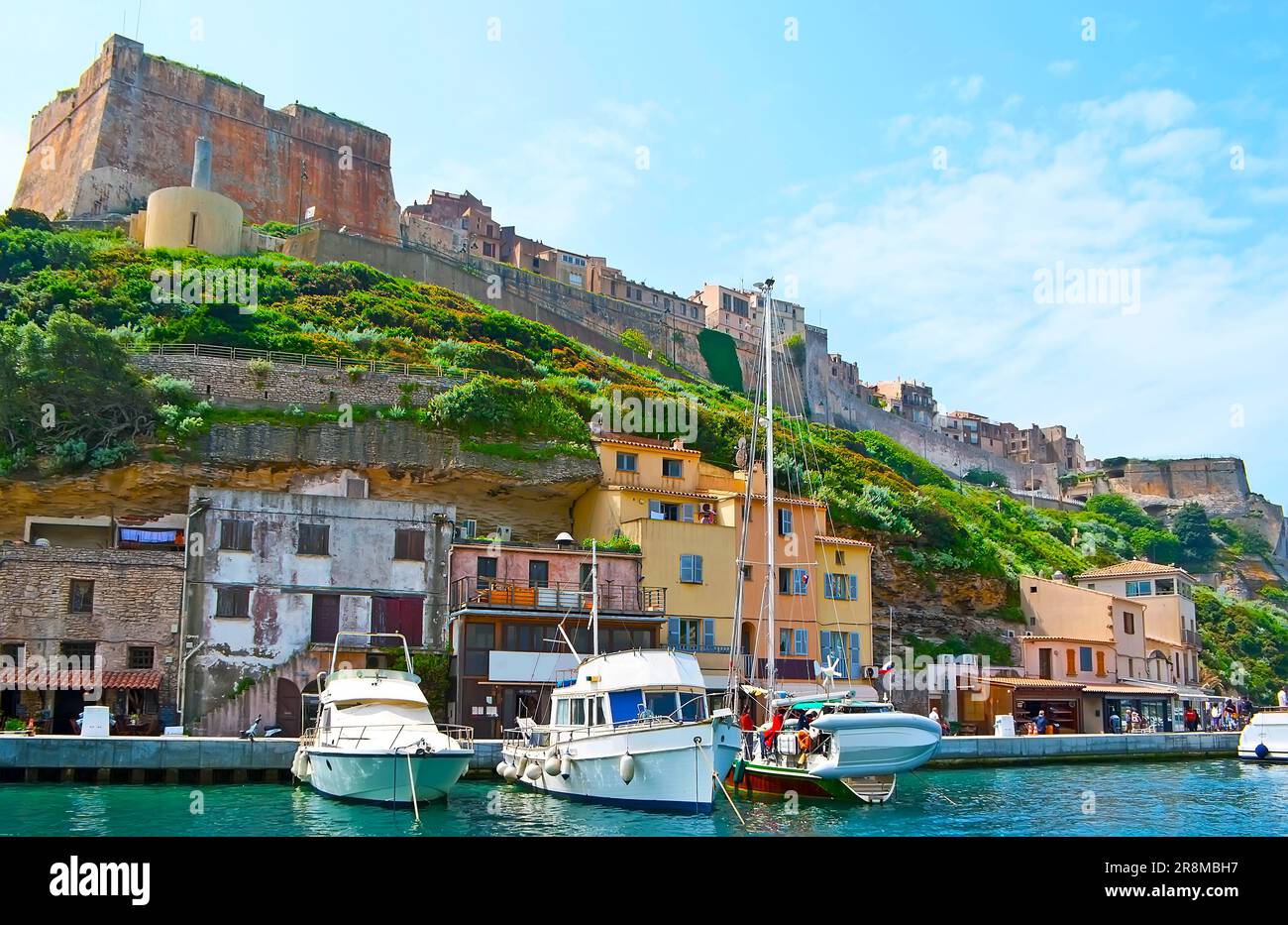 The old houses, built in rock along the harbor with medieval Citadel ...