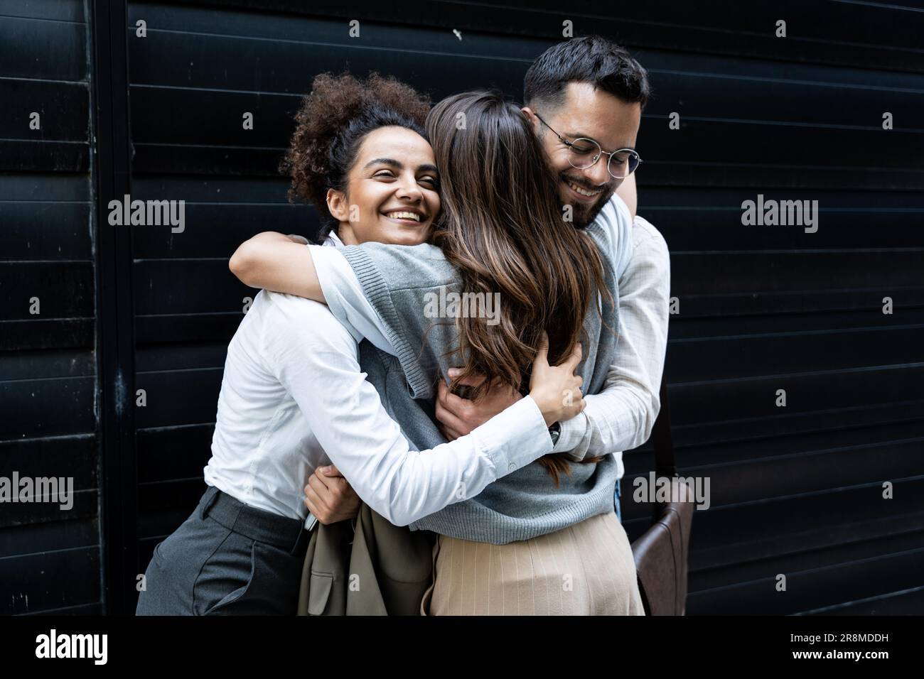 Cheerful businessman and businesswomen hugging each other in front of ...