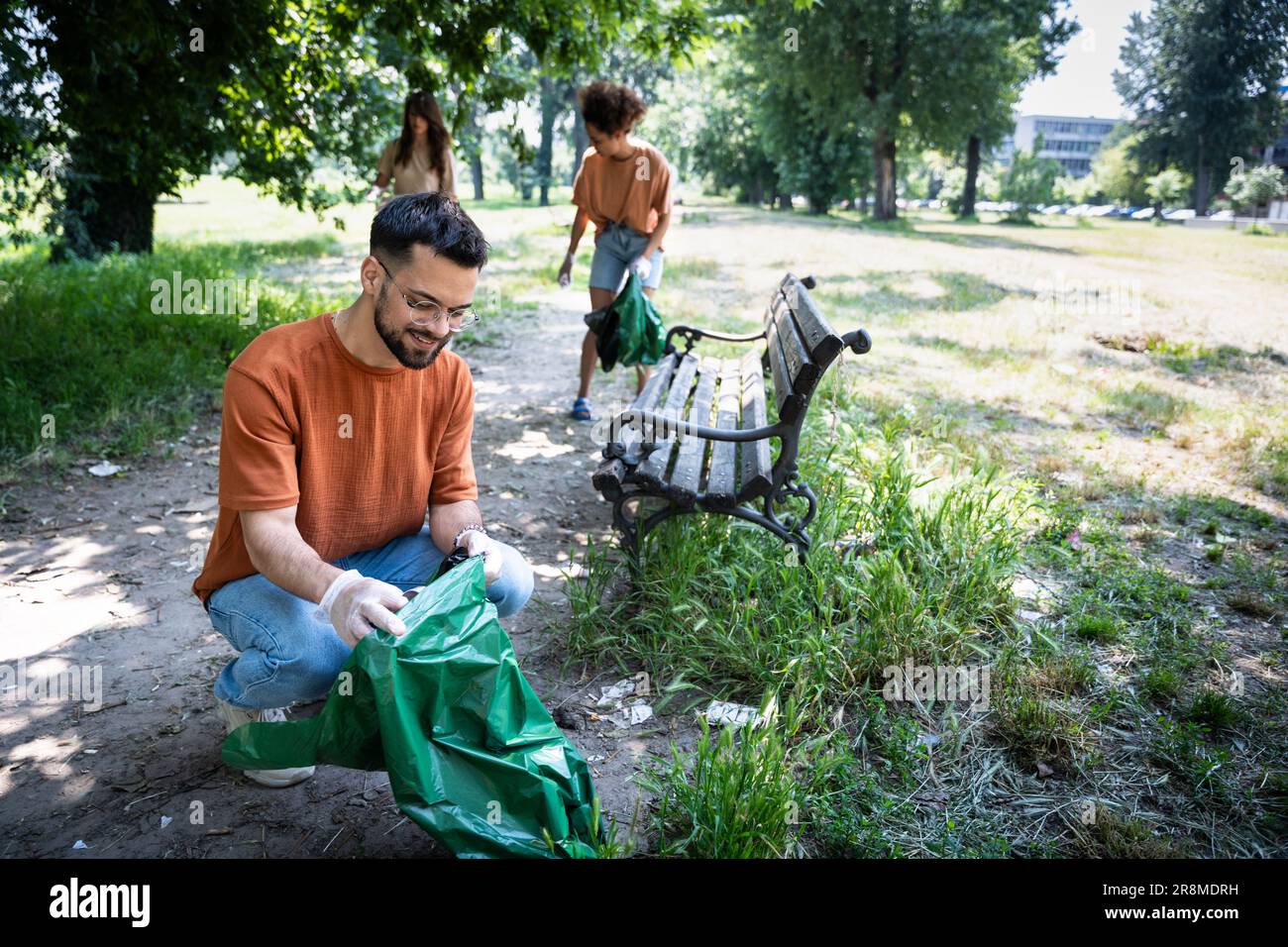 Young volunteers cleaning up park together, collecting trash and ...