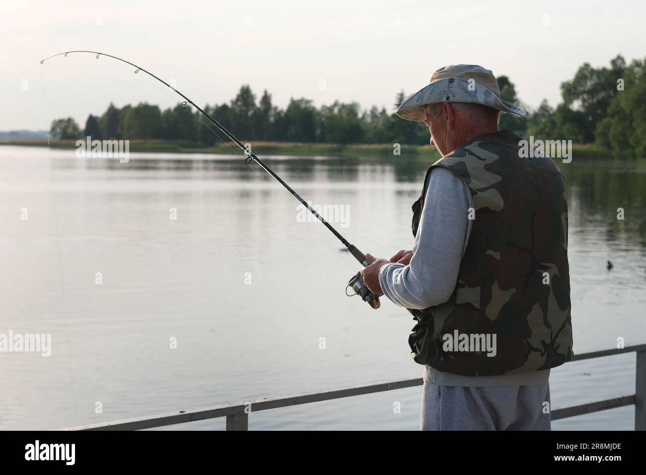 Old man fishing. Senior gray haired fisherman throws a spinning from ...