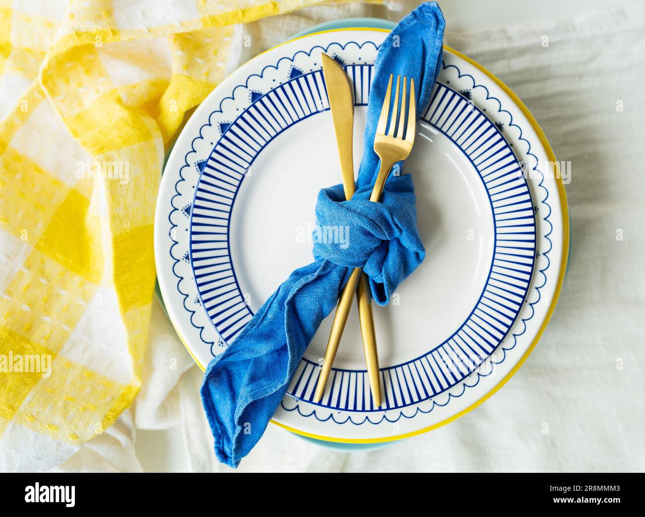 Serving design. Gold cutlery is tied with a blue napkin, on which the ...
