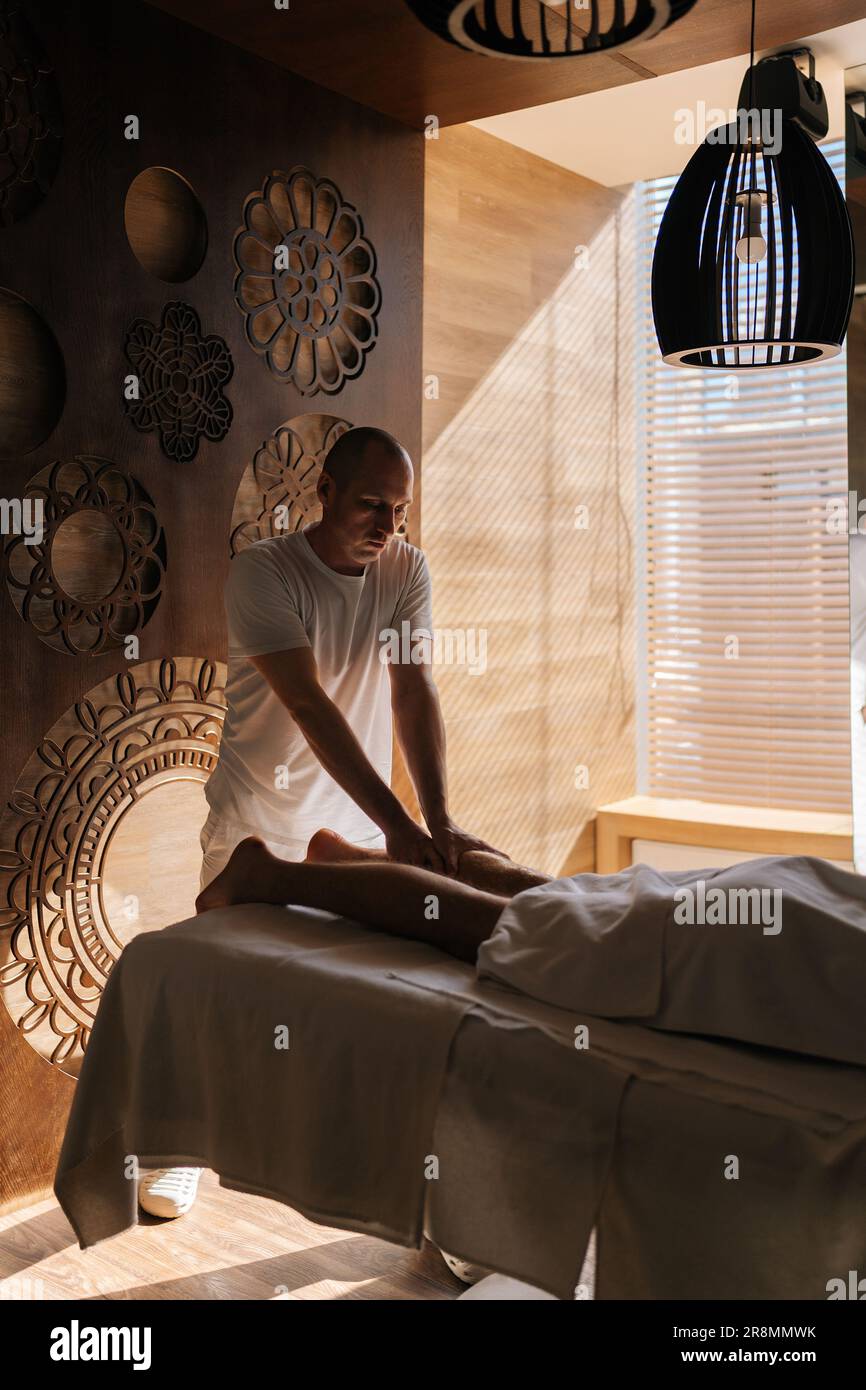 Vertical portrait of serious masseur male doing professional massage of ...