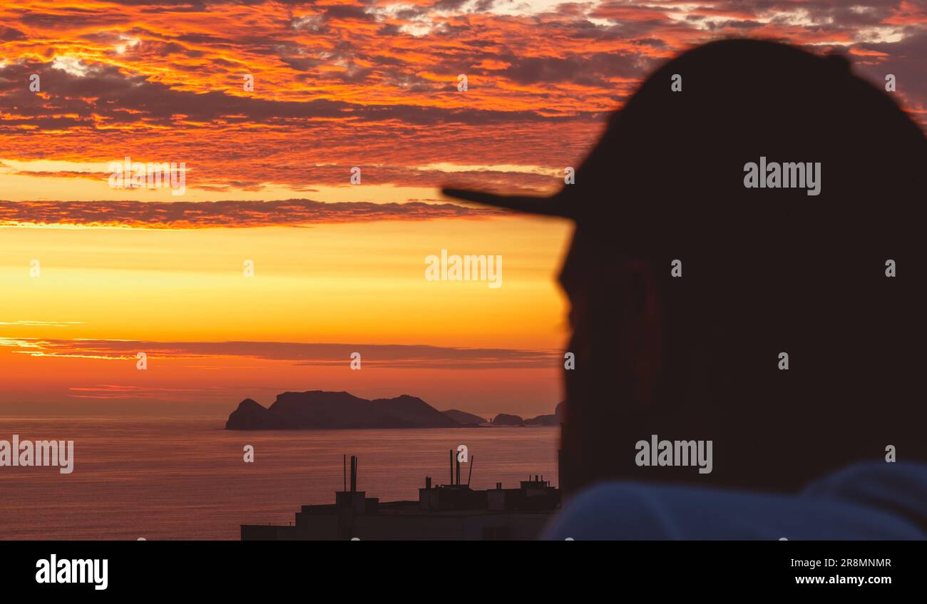Back view backlight portrait of a single men watching a sunset on the ...