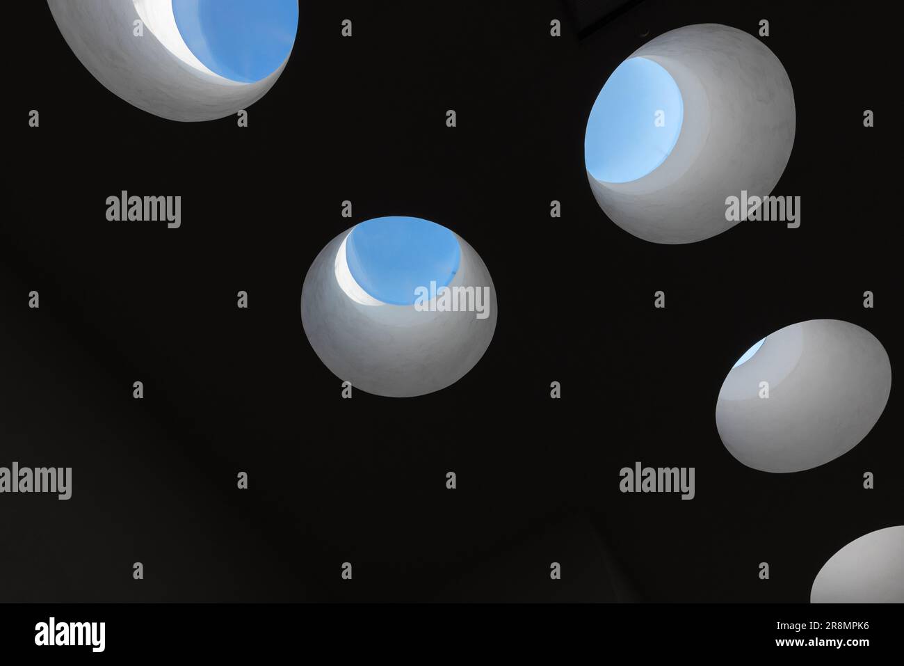 Dark ceiling with round skylight portals with blue sky behind, abstract ...