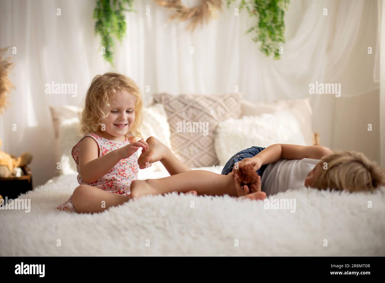 Cute sweet toddler children, tickling feet on the bed, laughing and ...