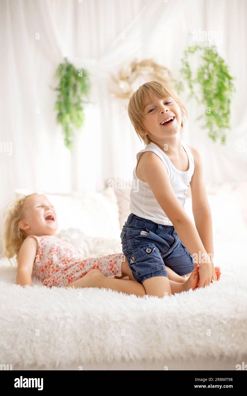 Cute sweet toddler children, tickling feet on the bed, laughing and ...