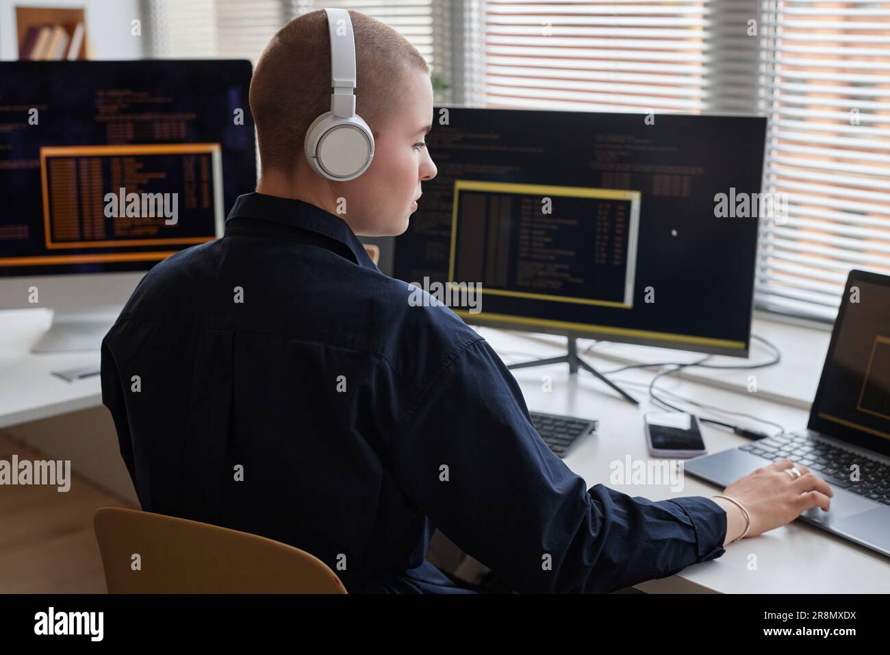 Side view portrait of bald young woman wearing headphones and using ...