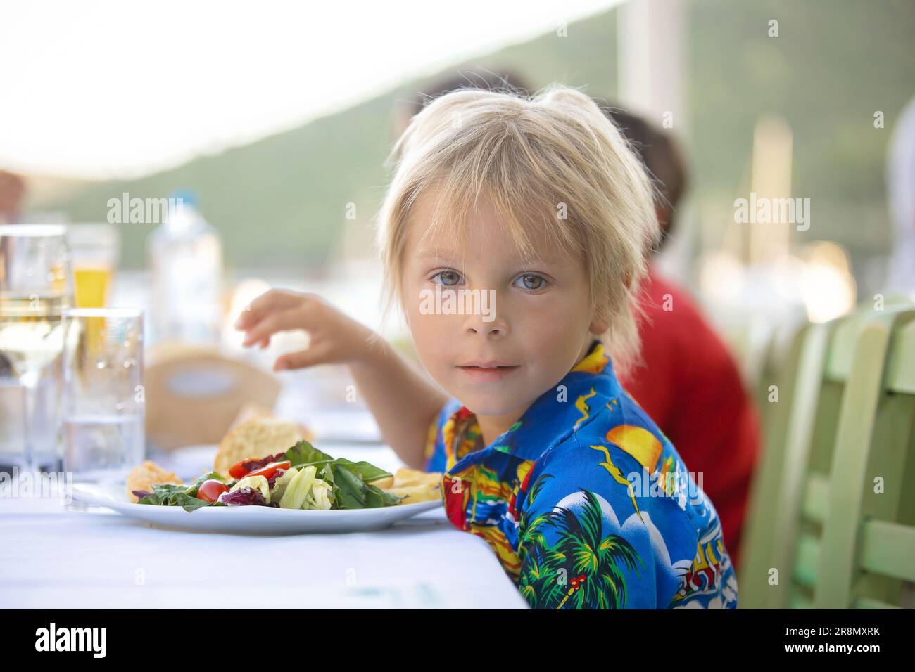 Sweet child, sitting in restaurant summertime outdoor, eating seafood ...