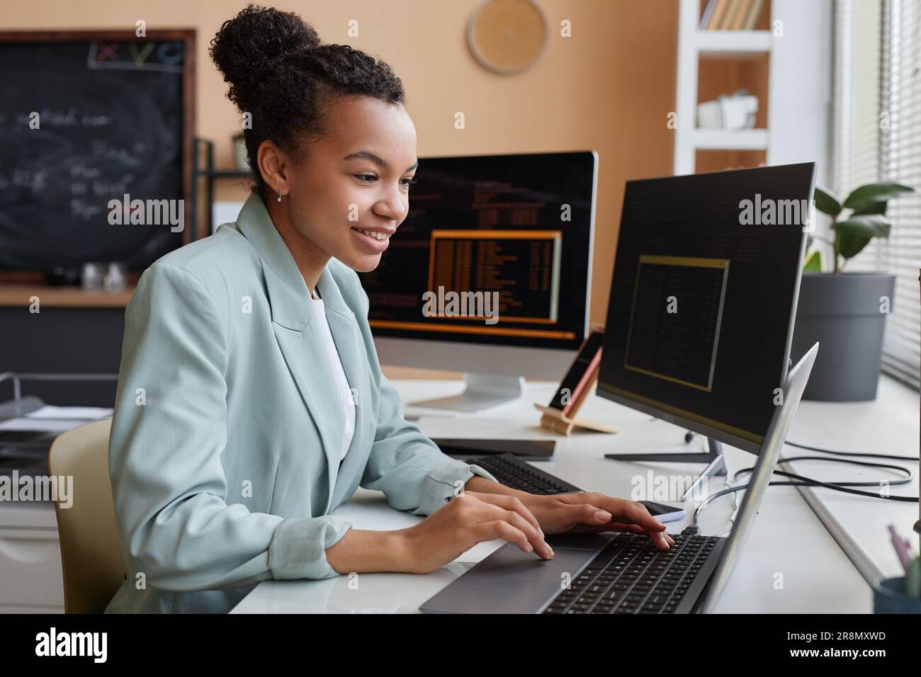 Side view portrait of young black woman programming code and using ...