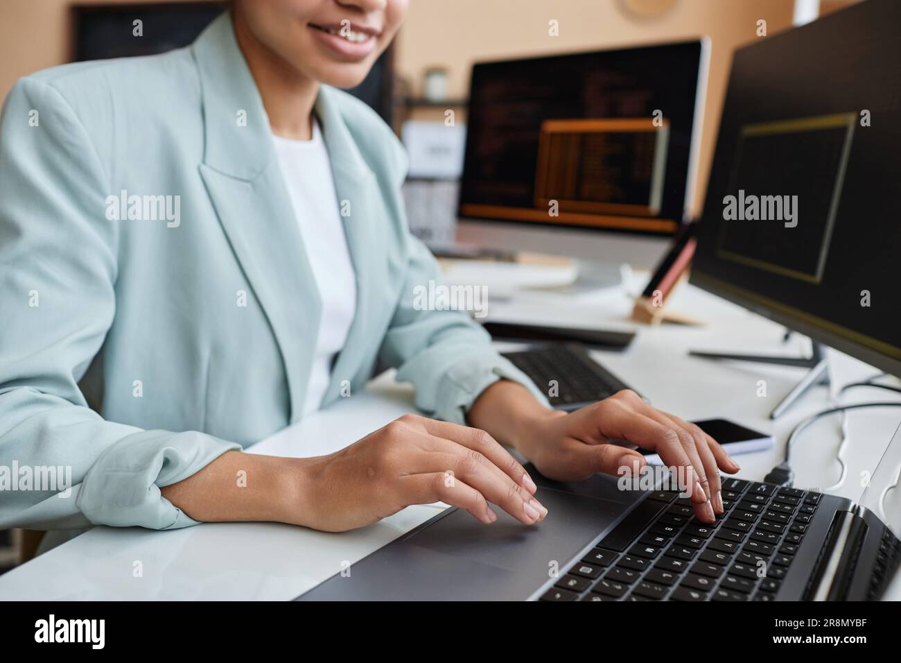 Closeup of smiling young black woman programming code and using ...