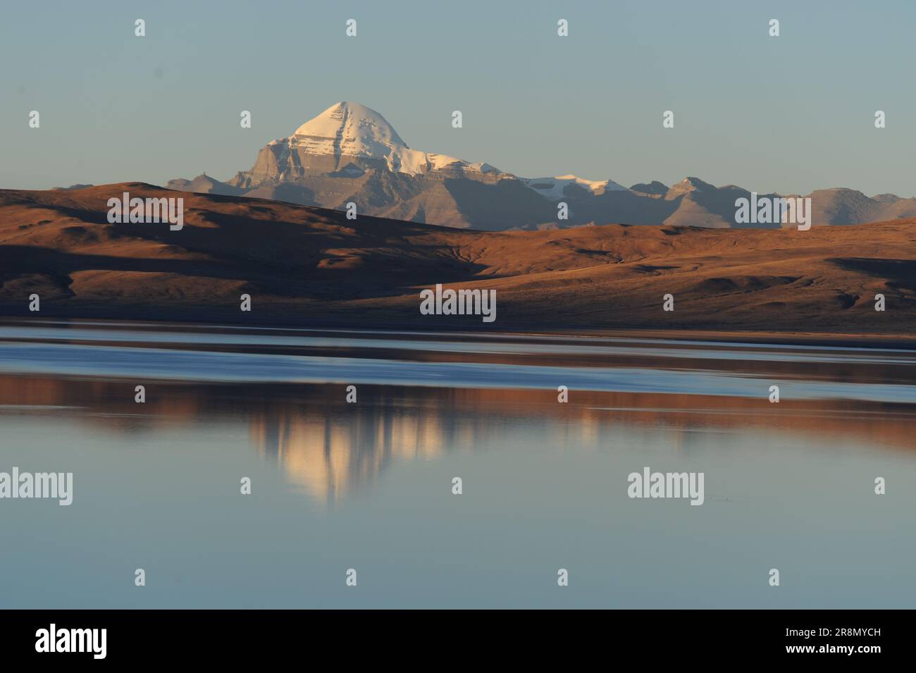 Mount Kailash reflected in a tranquil lake at sunset, creating a ...