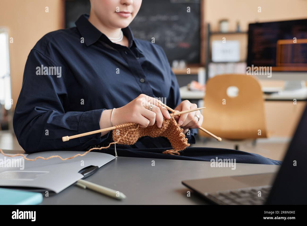 Closeup of gen Z young woman knitting or crocheting at workplace in ...