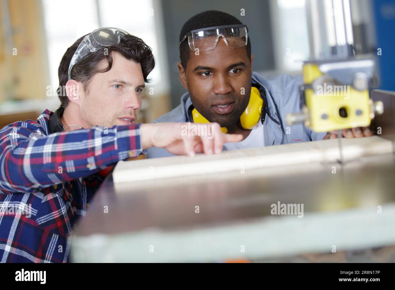 carpenter training male apprentice to use mechanized saw Stock Photo ...