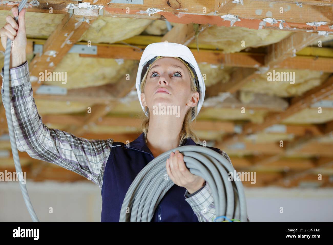 female electrician passing cable through roof joists Stock Photo - Alamy