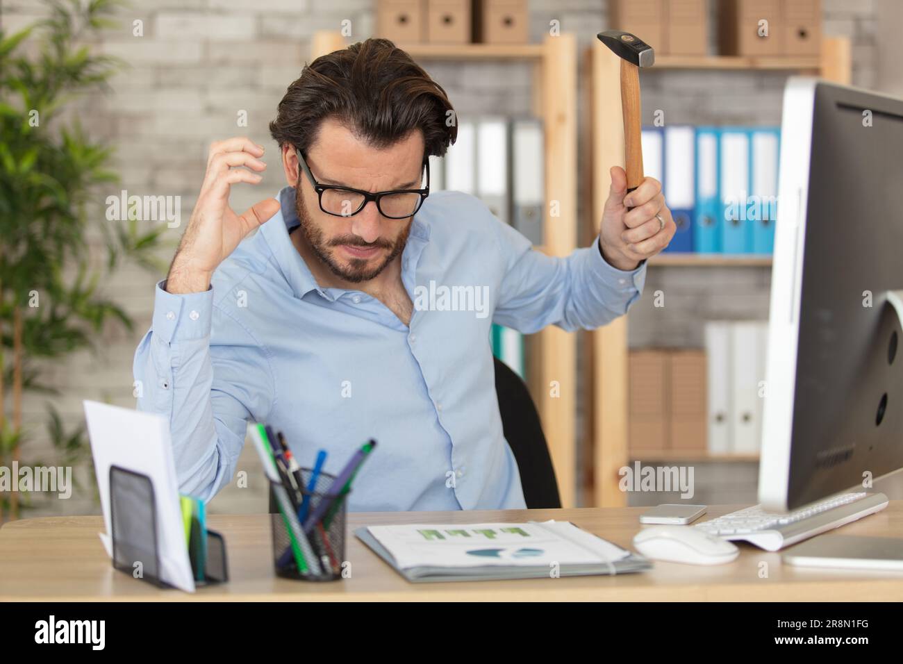 frustrated young man with a hammer in front of computer Stock Photo - Alamy