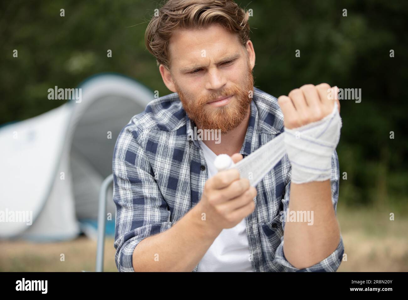 man applying an arm bandage during camping Stock Photo - Alamy