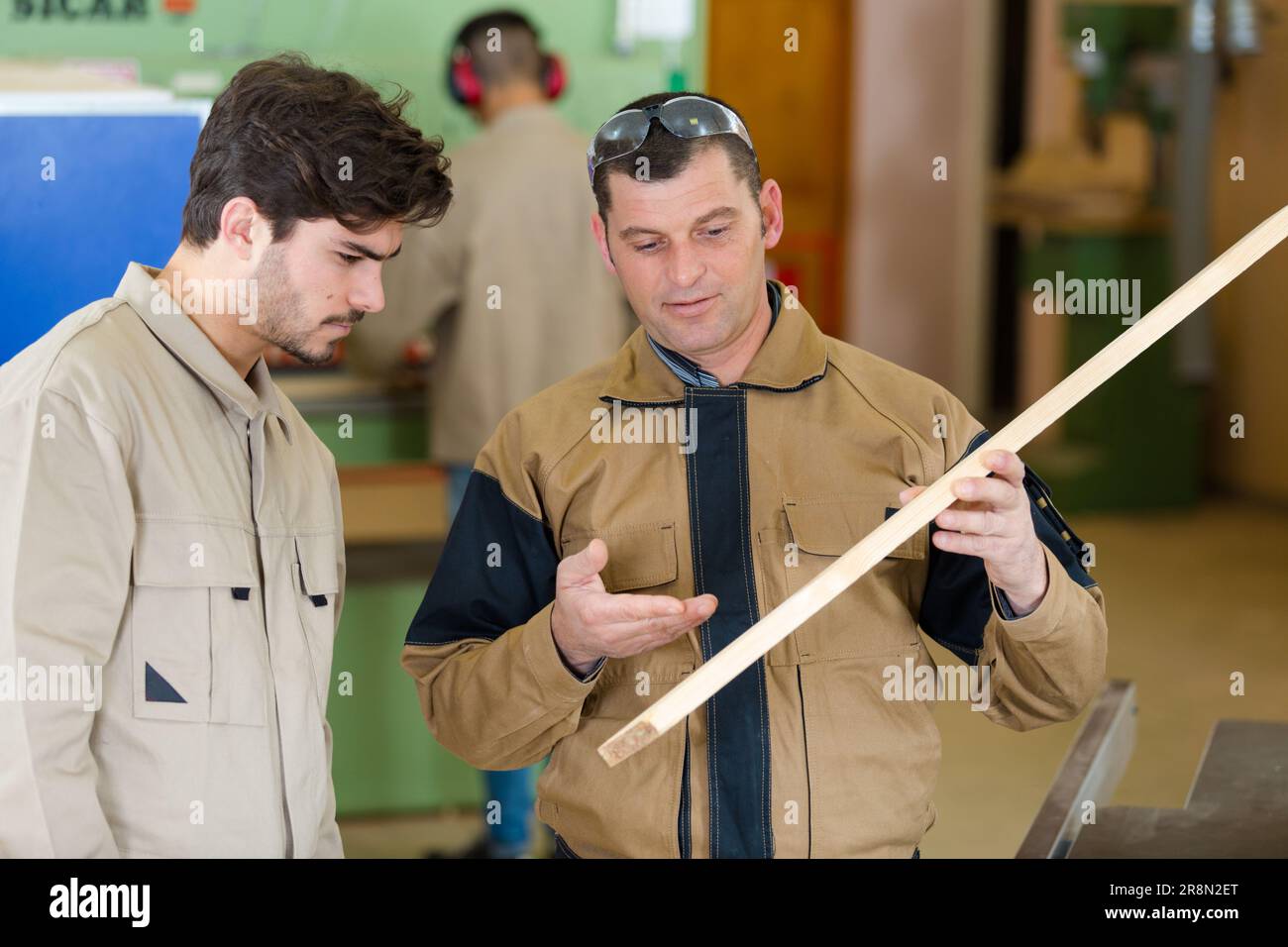 woodworker holding a plank to show to apprentice Stock Photo - Alamy
