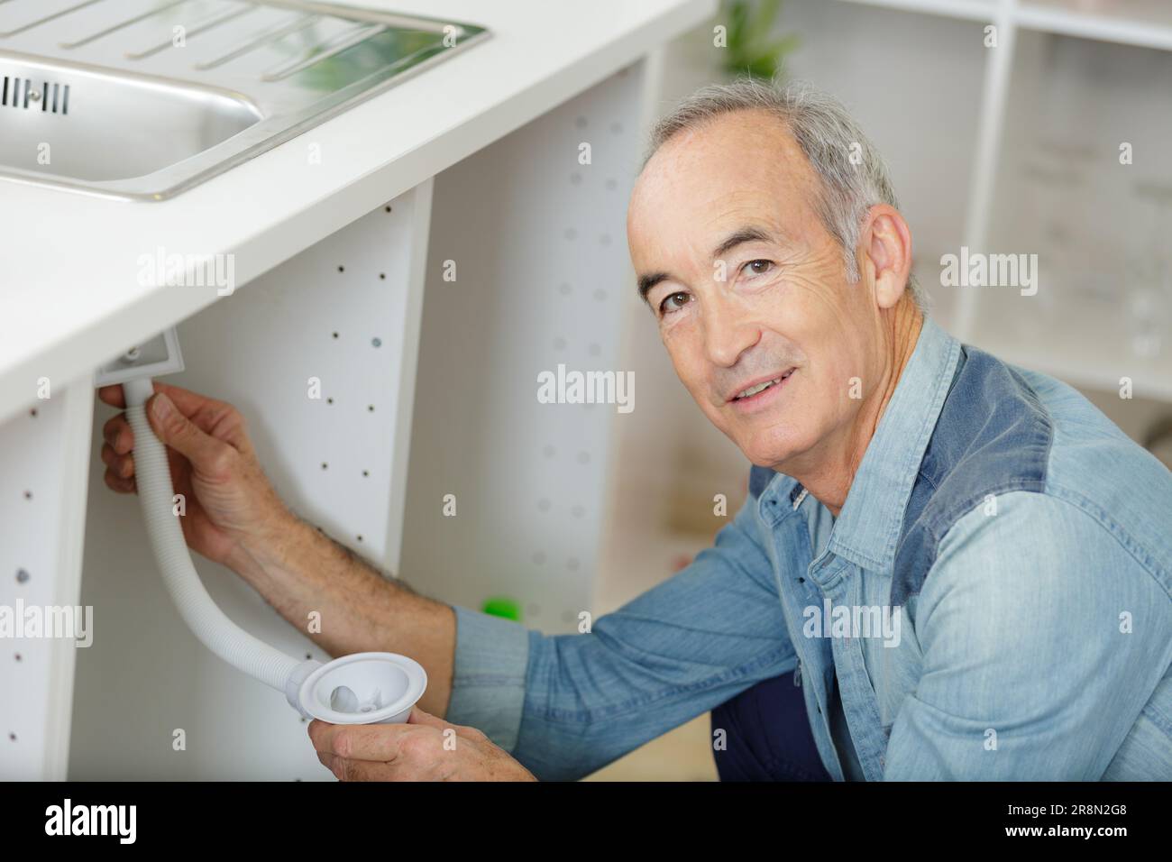 man looking under the sink Stock Photo - Alamy