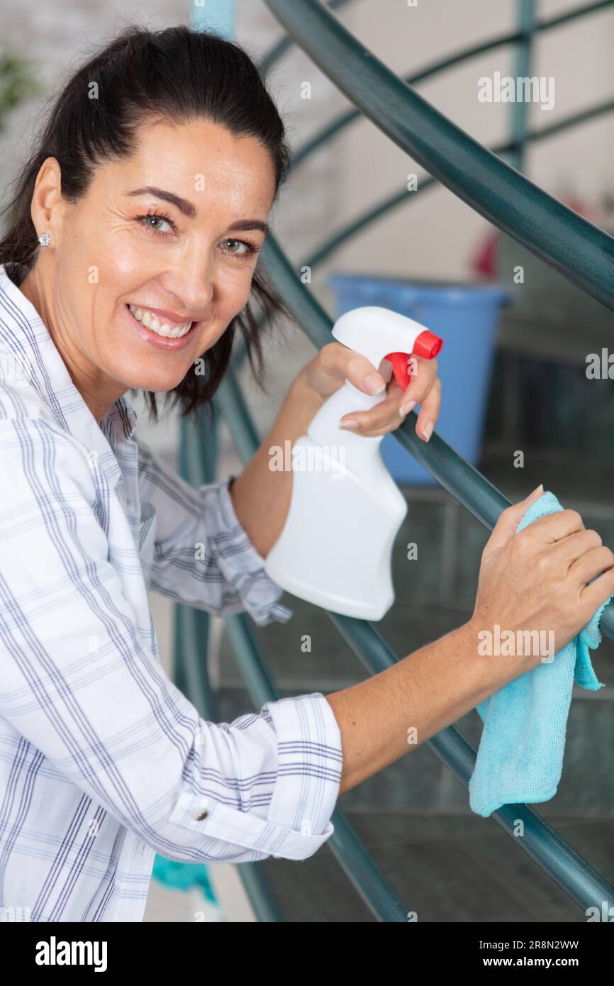 long-haired housewife cleaning stair railings with rag at home Stock ...