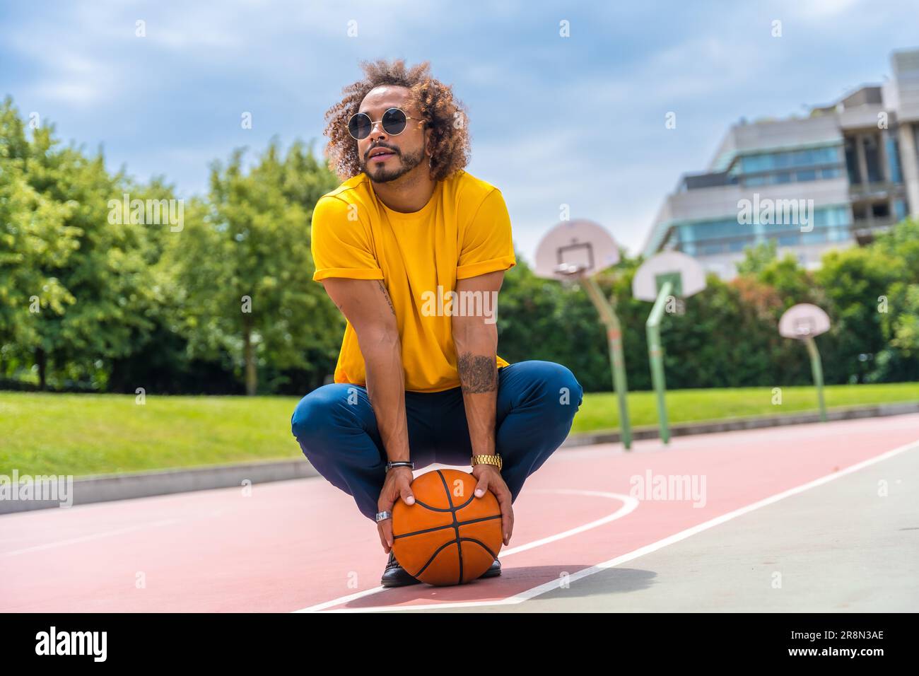 Portrait of an afro-haired man in a yellow t-shirt with a basketball ...