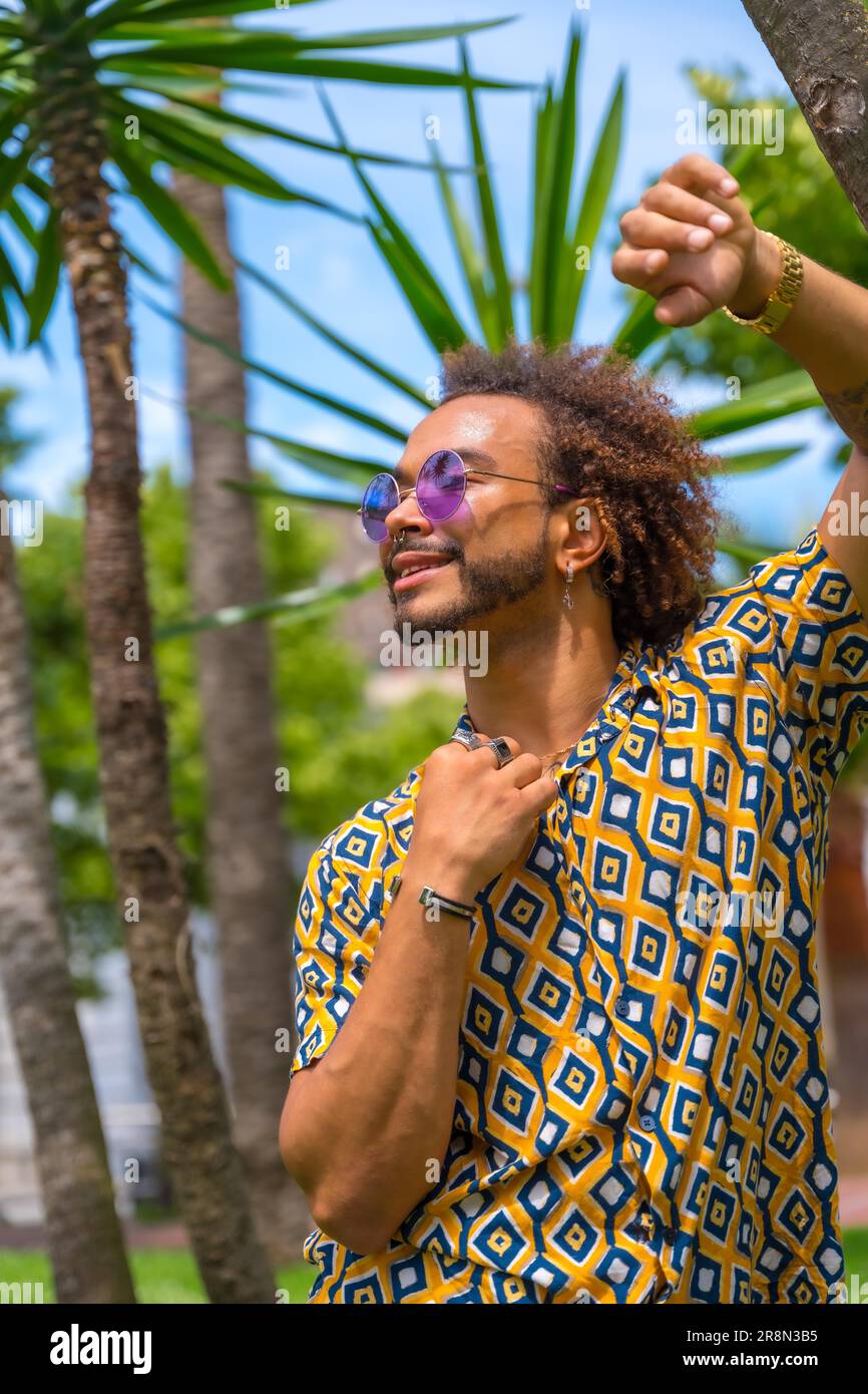 Portrait of afro haired man on summer vacation next to some palm trees ...