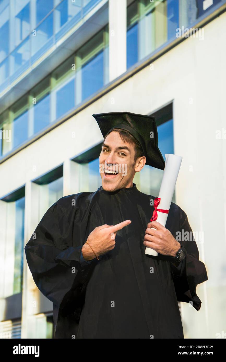 Happy graduated man wearing a bachelor gown and a black mortarboard and ...