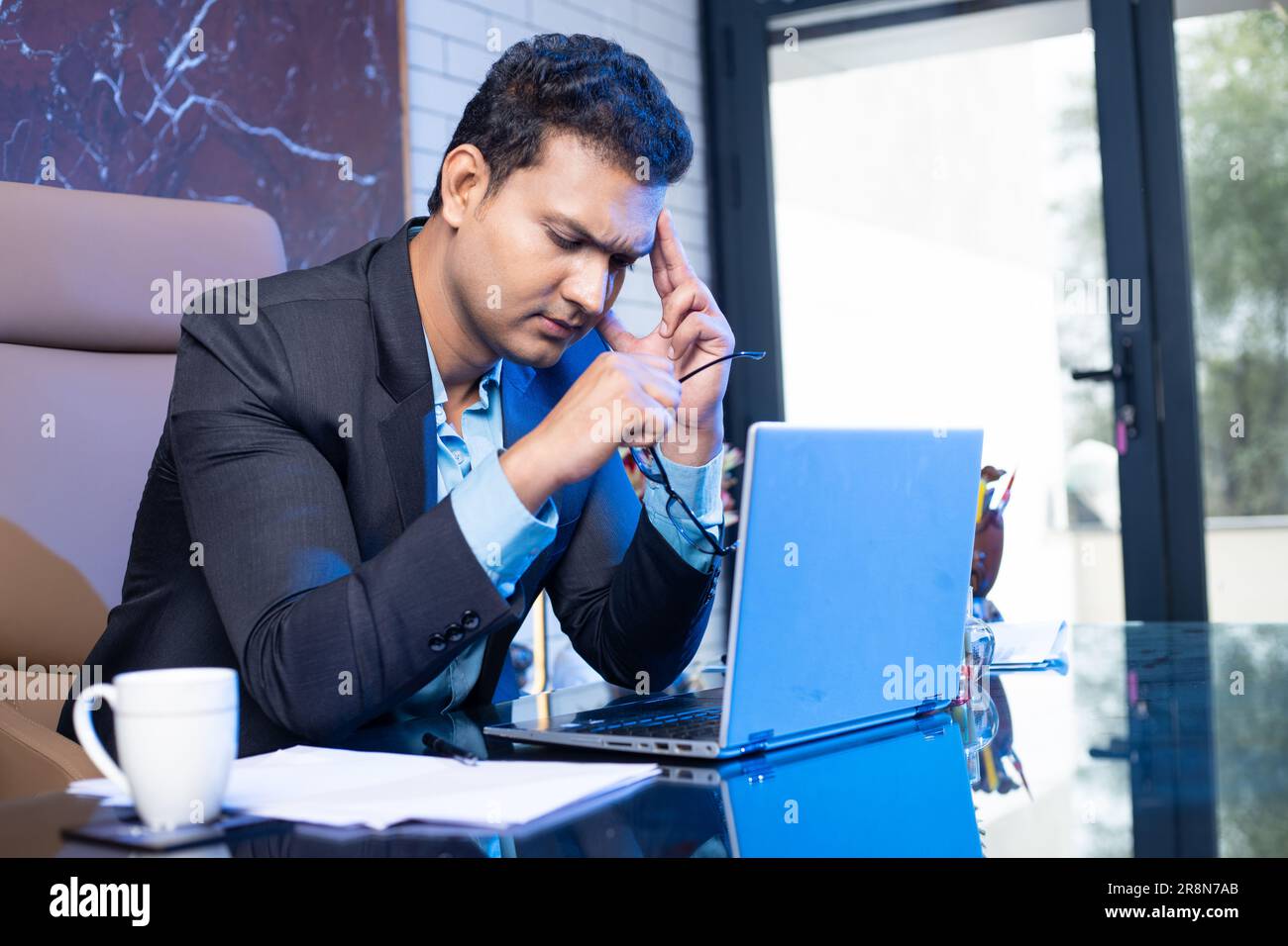 Stressed indian businessman working on laptop computer in office ...