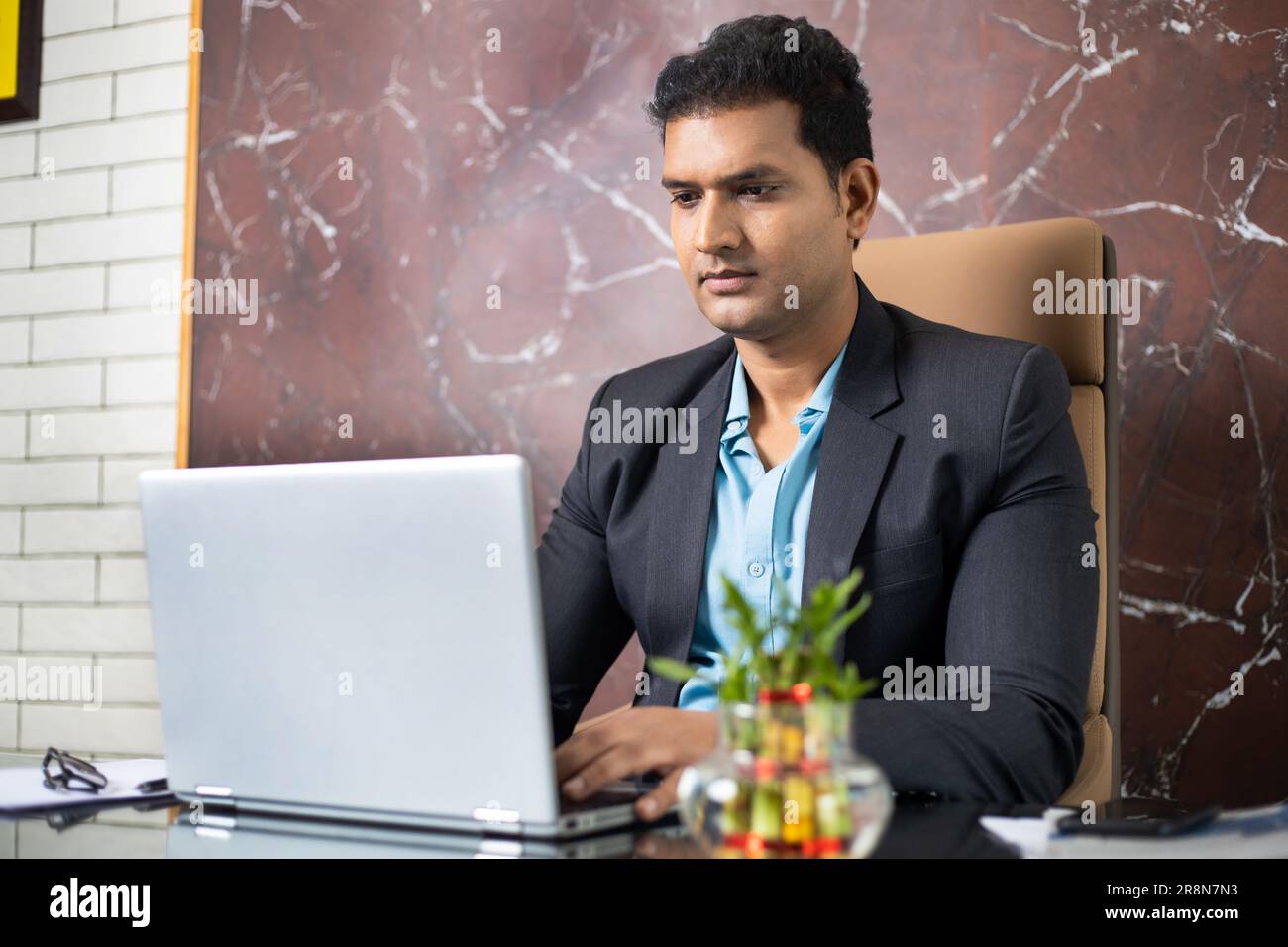 Successful handsome indian businessman working on laptop computer in ...