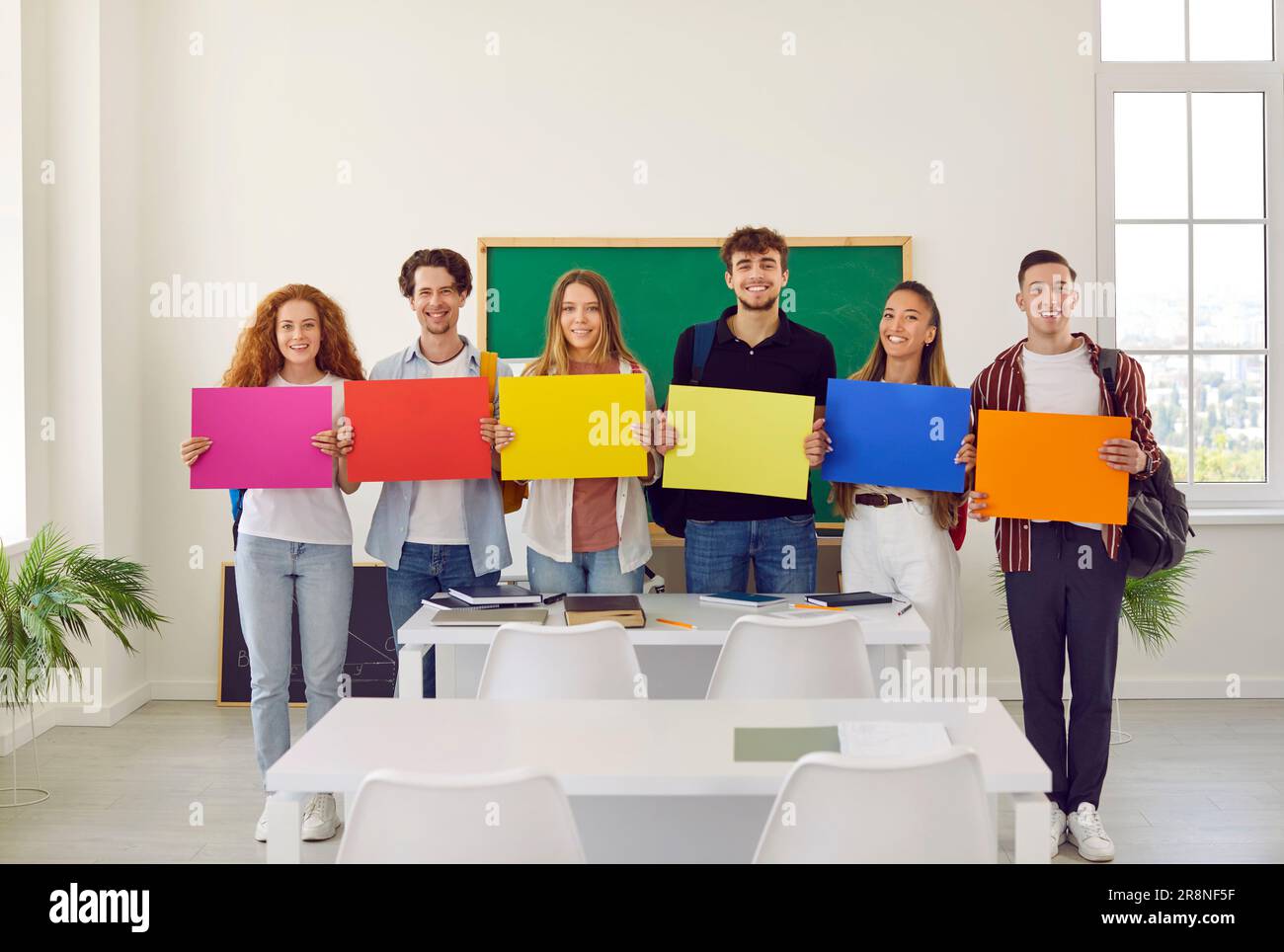 Smiling college students showing blank colorful posters with which to ...
