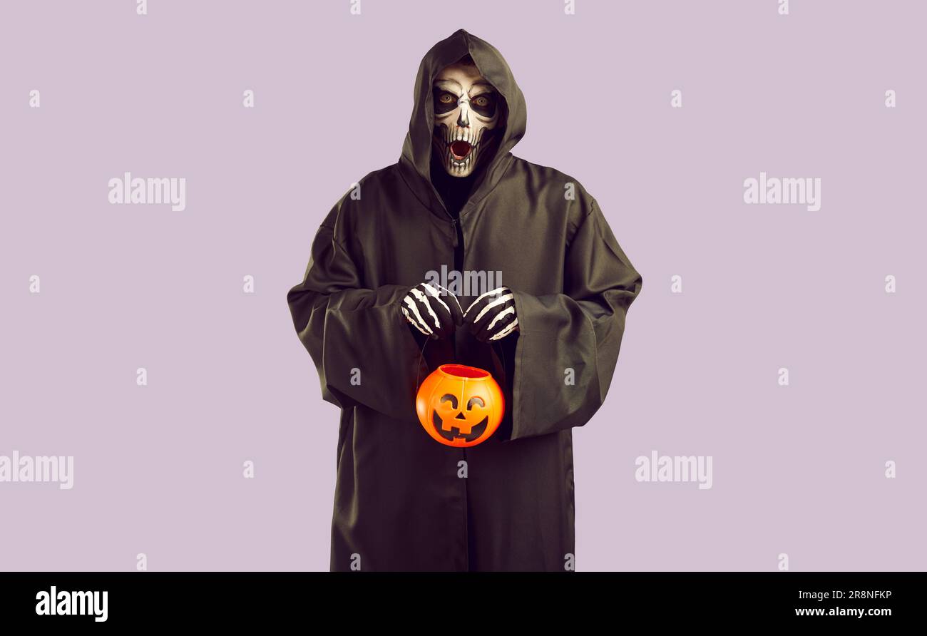Man in grim reaper costume with creepy facial expression collects candy ...