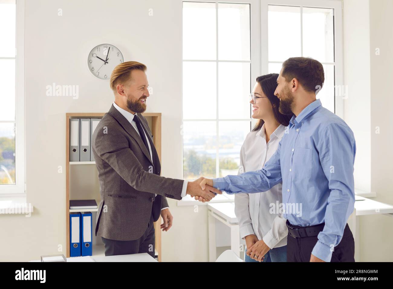 Bank employee shakes hands with couple after successfully signing ...