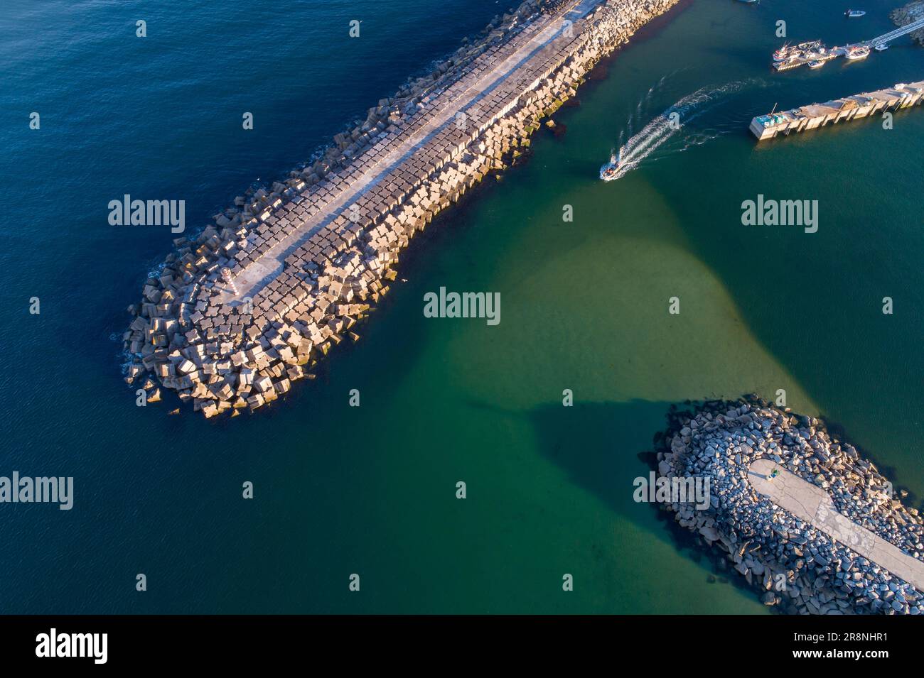 zenithal drone view of a harbor breakwater and a fishing boat at sea ...
