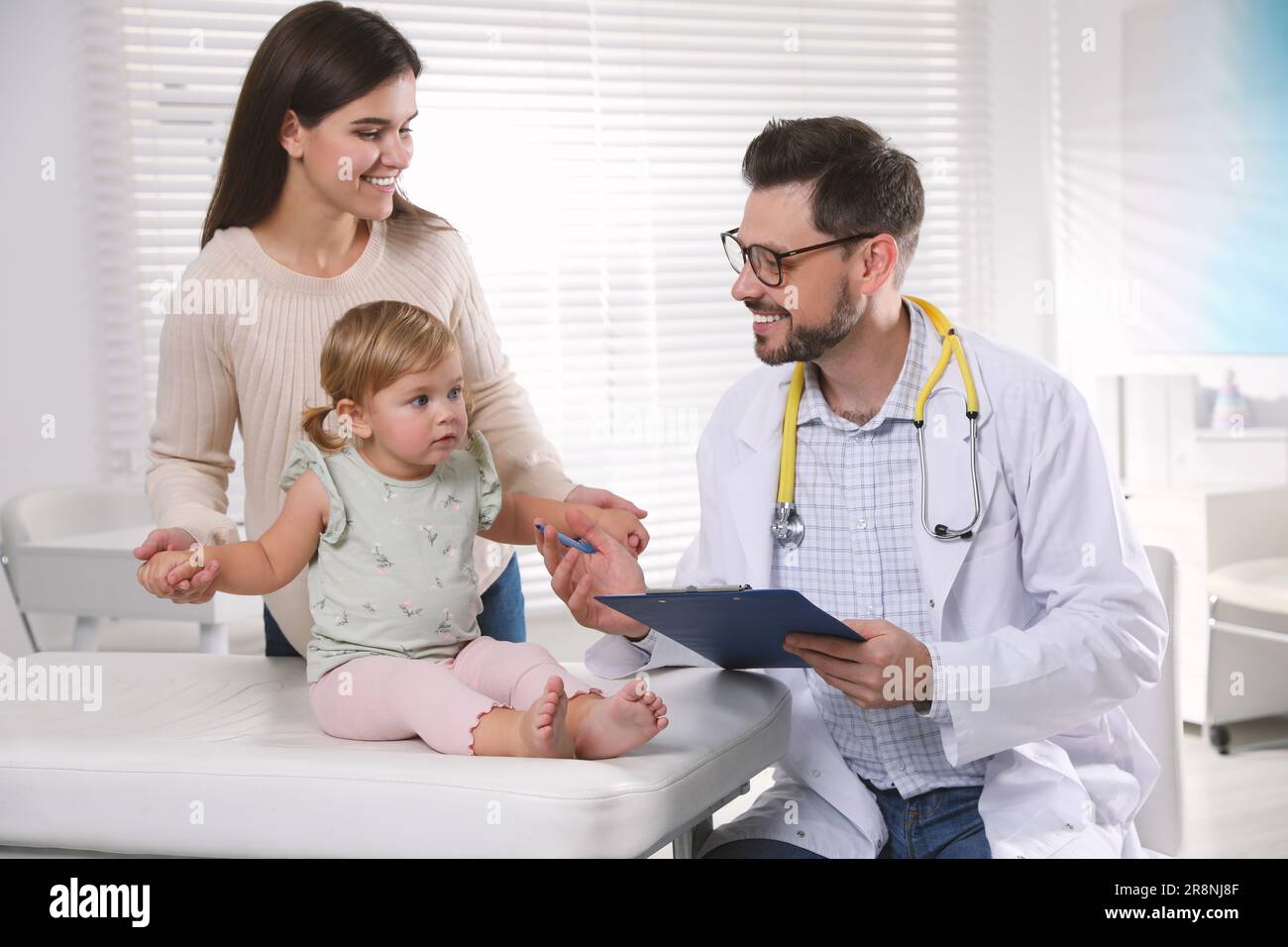Mother and her cute baby having appointment with pediatrician in clinic ...