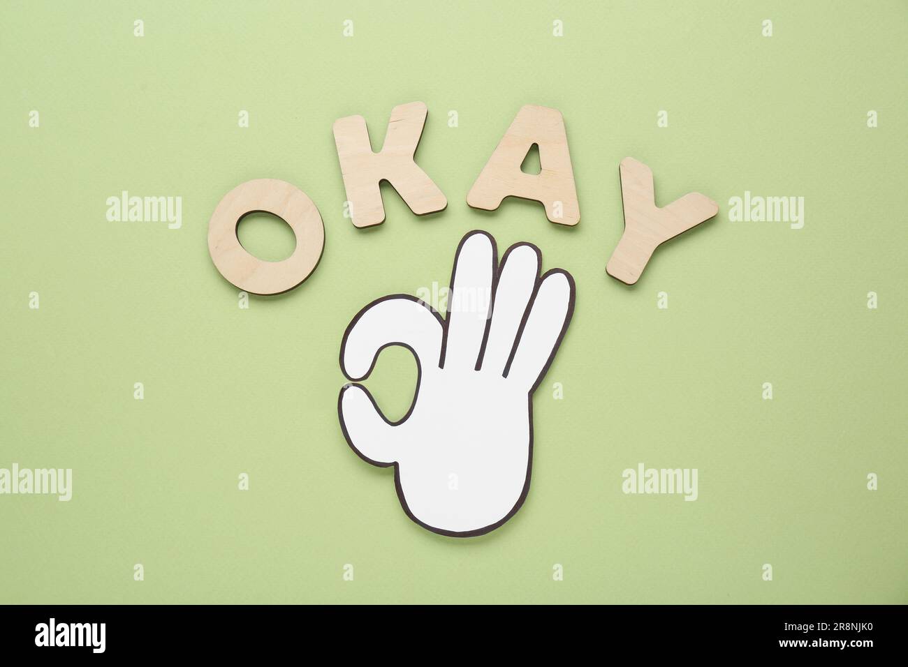 Word Okay made of wooden letters and paper cutout (OK hand gesture) on ...