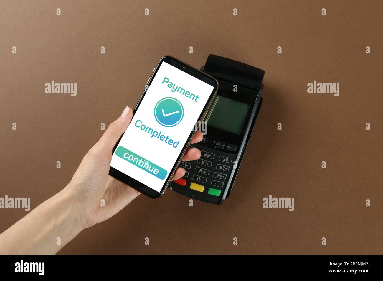 Woman using terminal for contactless payment with smartphone on brown ...