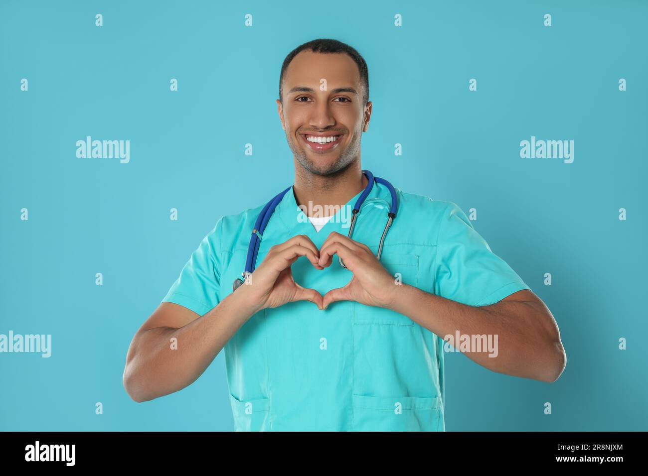 Doctor or medical assistant (male nurse) in uniform making heart with ...